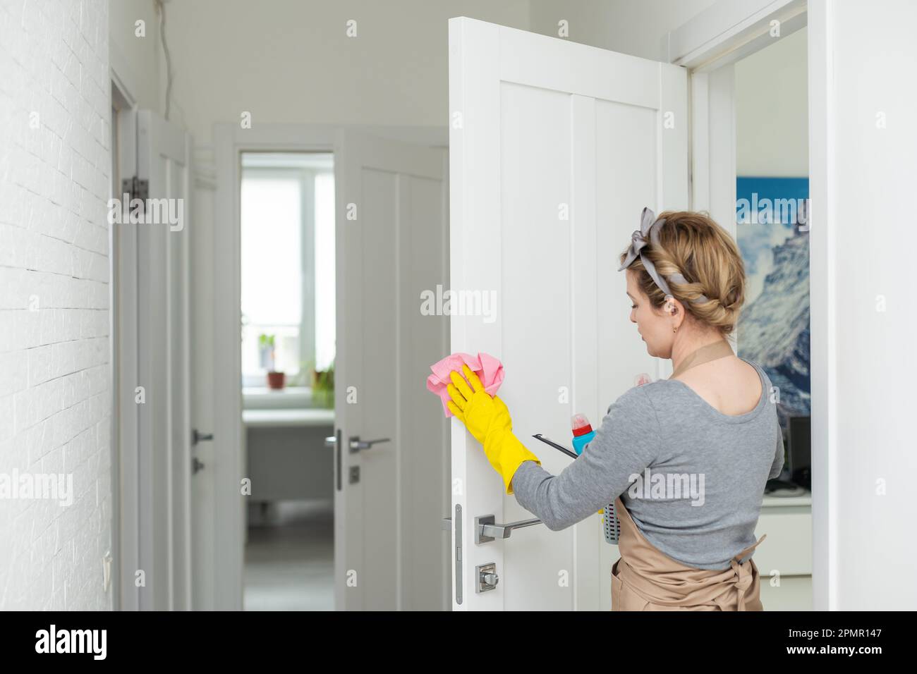 Woman cleaning and polishing the kitchen worktop with a spray detergent ...