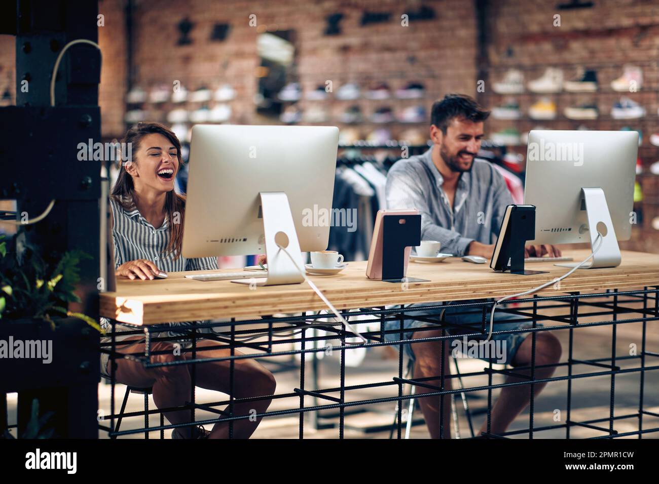Young workers in a shop working on the computer and laughing, having a good time at work ...