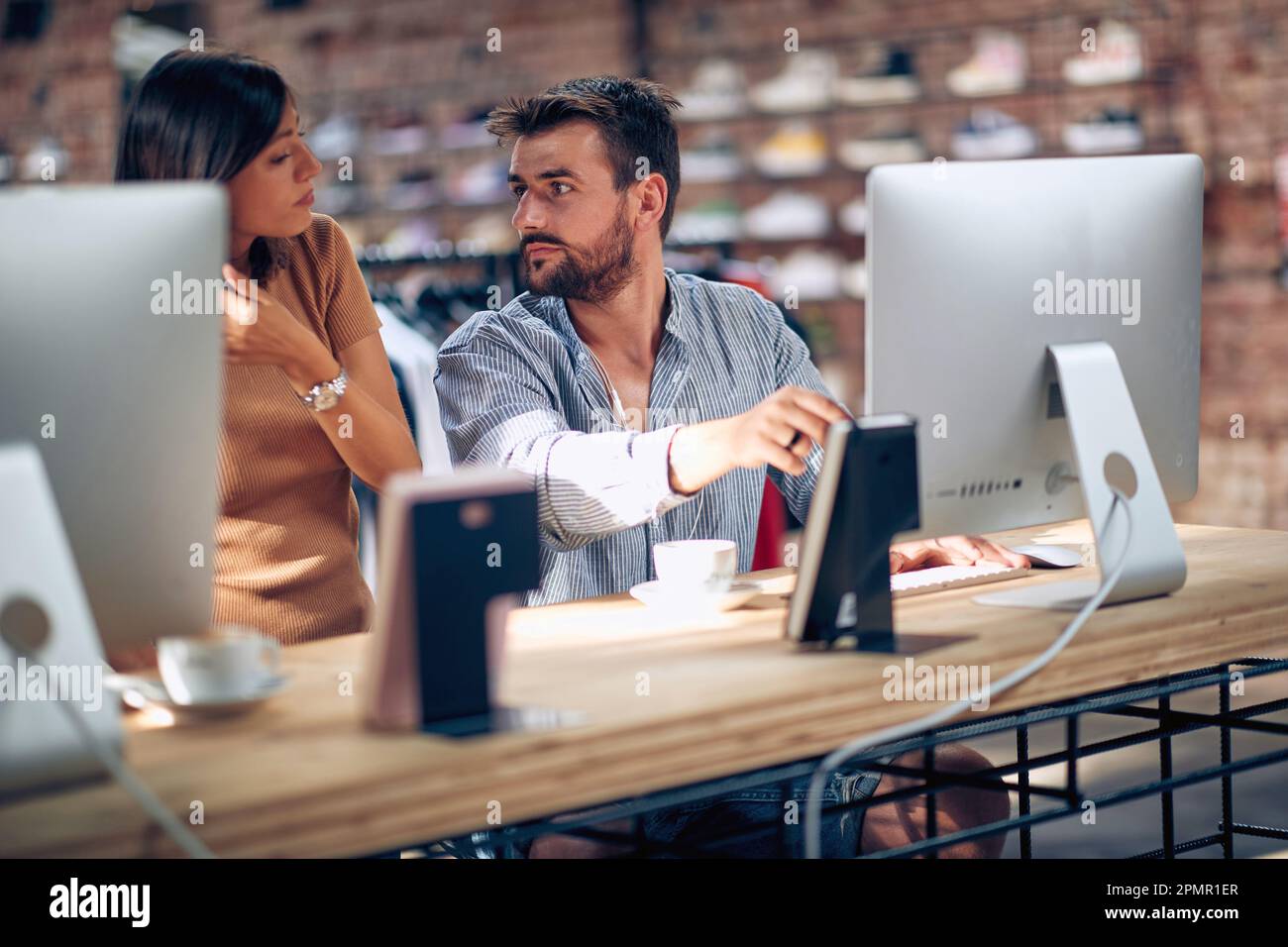 Young office workers looking at computer screen, man explaining his ...