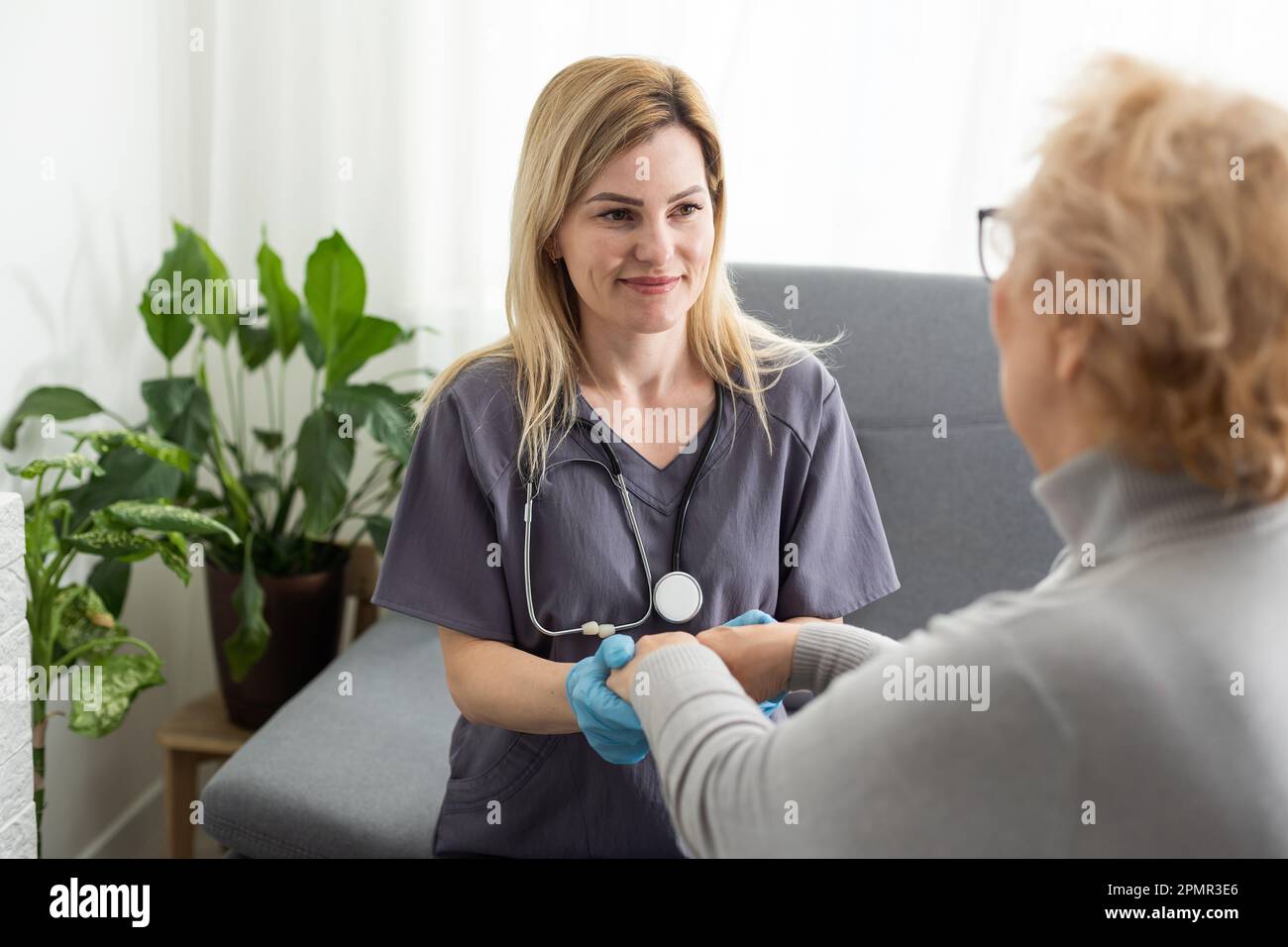 Caring young nurse doctor carer helping holding hands of happy disabled ...