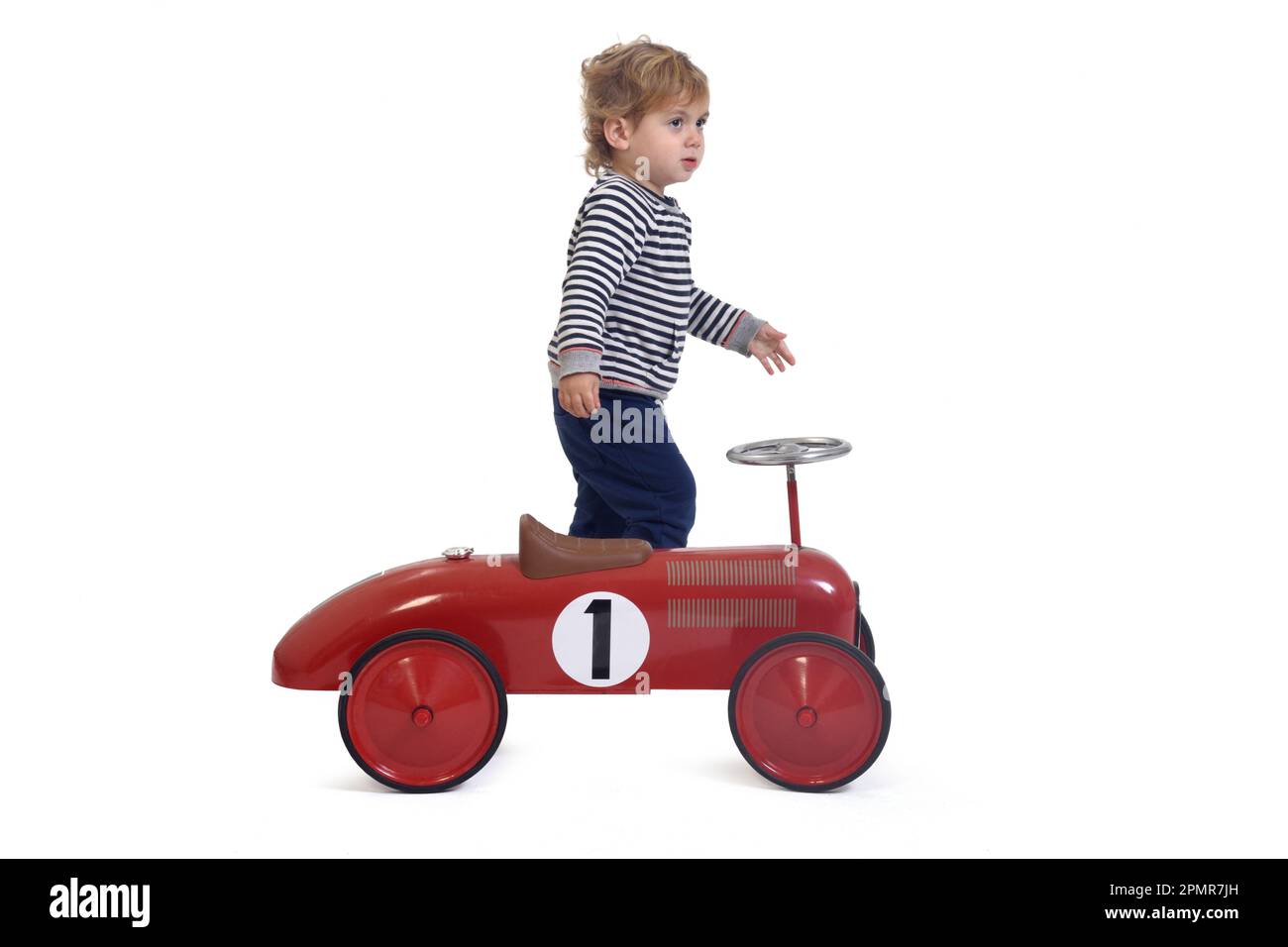 side view of a baby boy playing with car toy, the baby boy standing on ...
