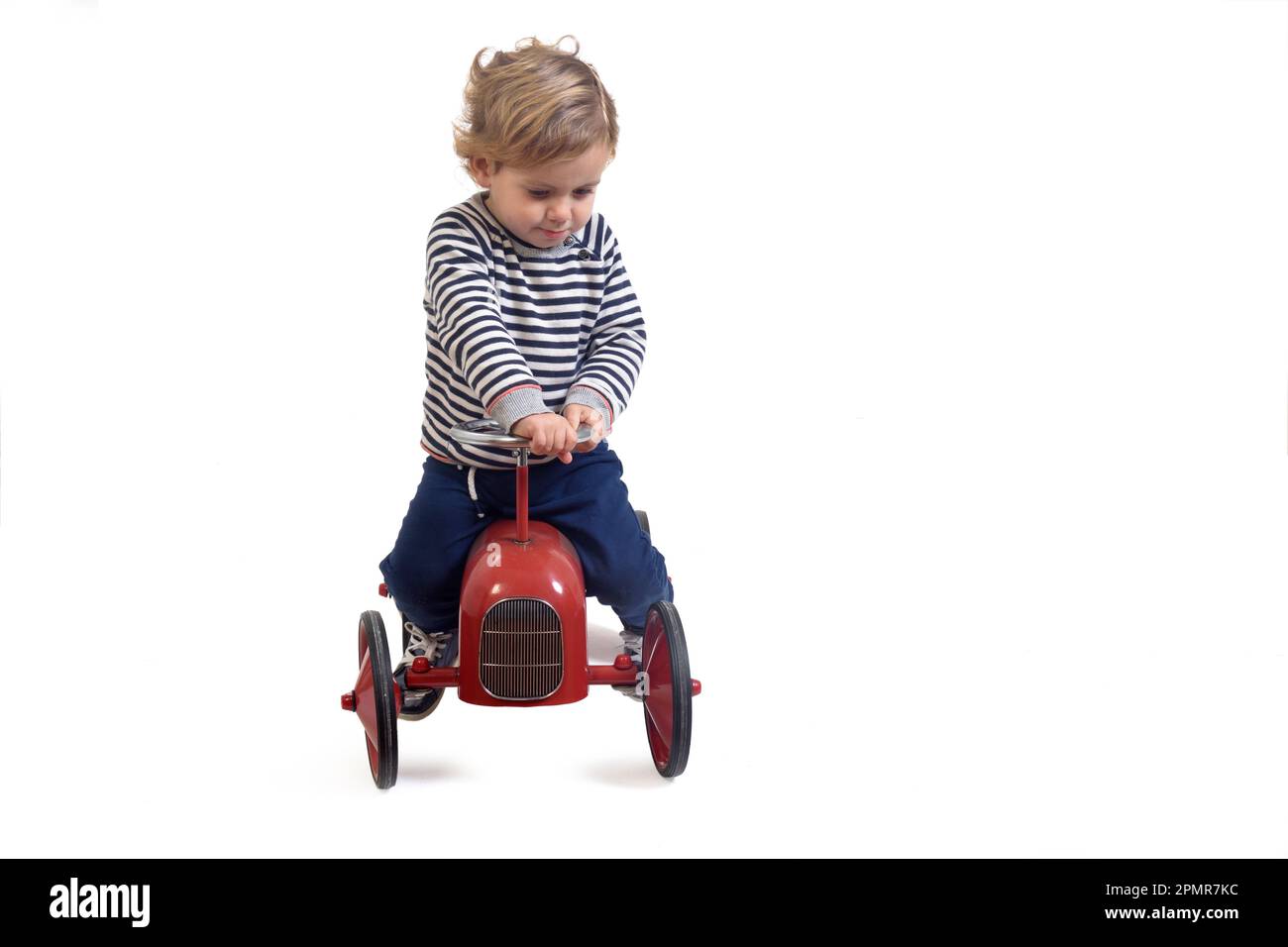front view of a baby boy playing and driving a car toy on white ...