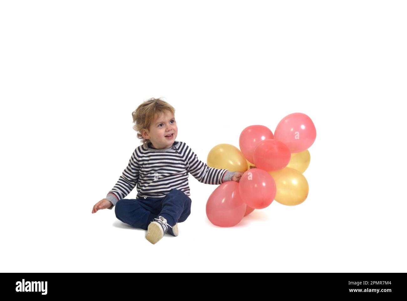 front view of baby boy playing with a air balloon on ground on white ...