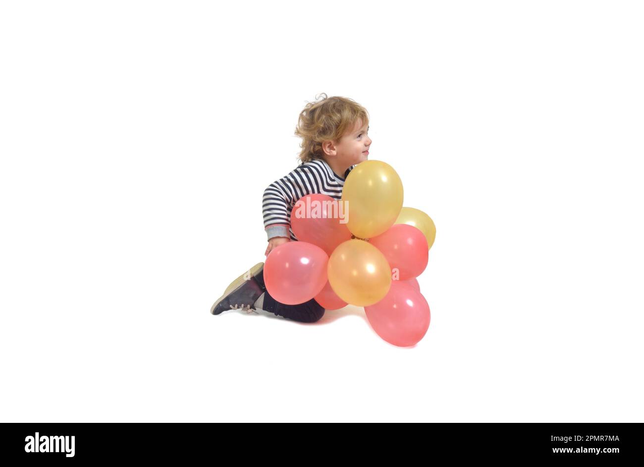 side view of baby boy playing with a air balloon on ground on white ...