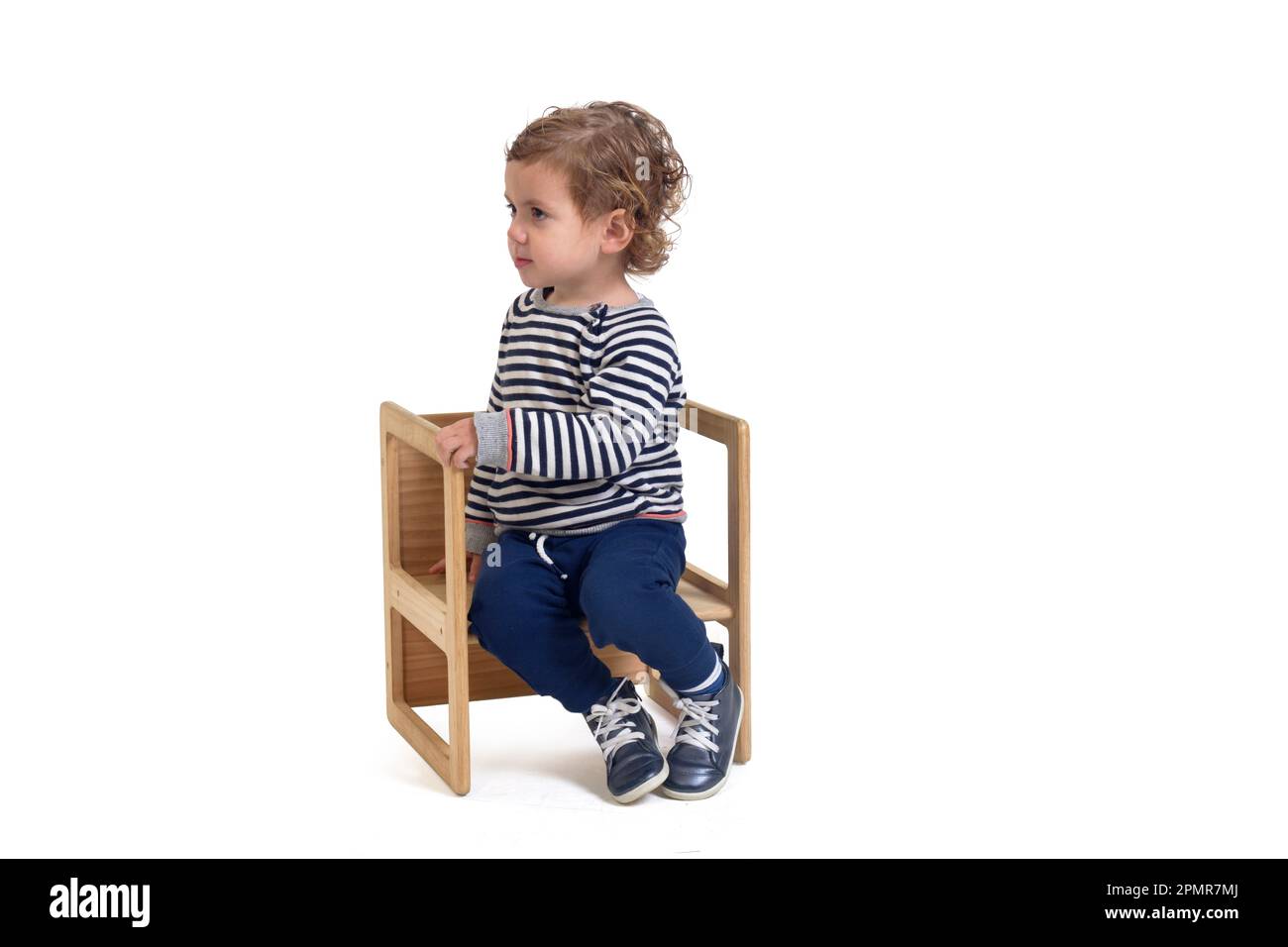 side view of a baby boy sitting on chair on white background Stock ...