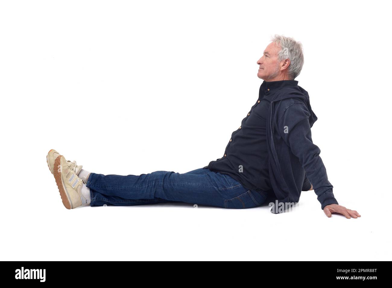 side view of a man sitting on the floor with his legs stretched out on ...