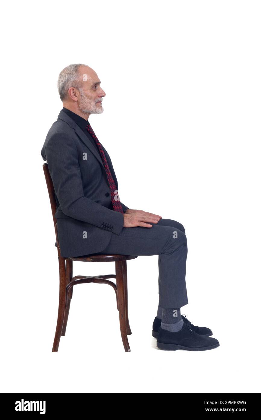 side view of a man sitting on chair with suit and tie looking on white ...