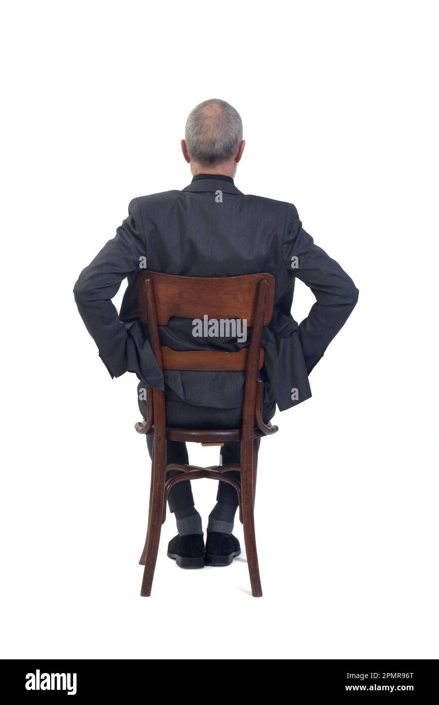 back view of a man sitting on chair with suit and arms akimbo on white ...