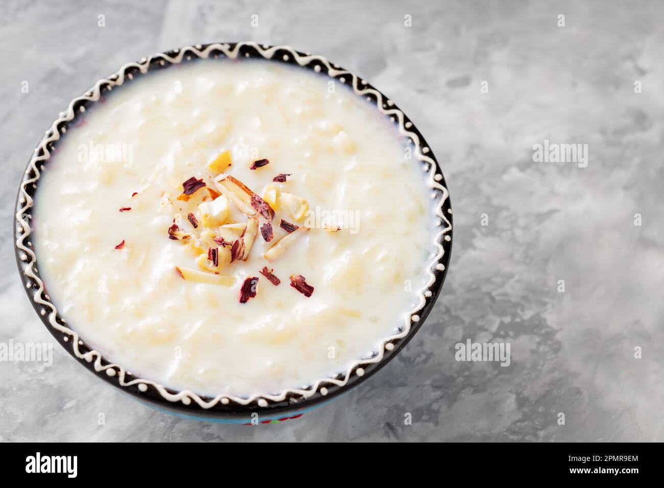 Bowl with rice pudding on a gray background. Rice kheer with cashew ...
