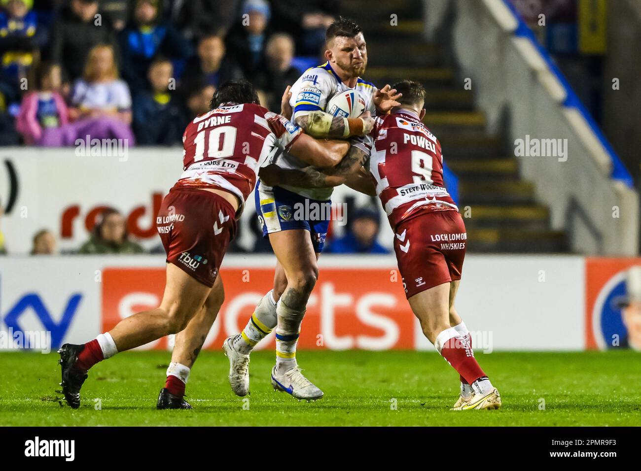 Josh McGuire #13 of Warrington Wolves is tackled by Sam Powell #9 and ...