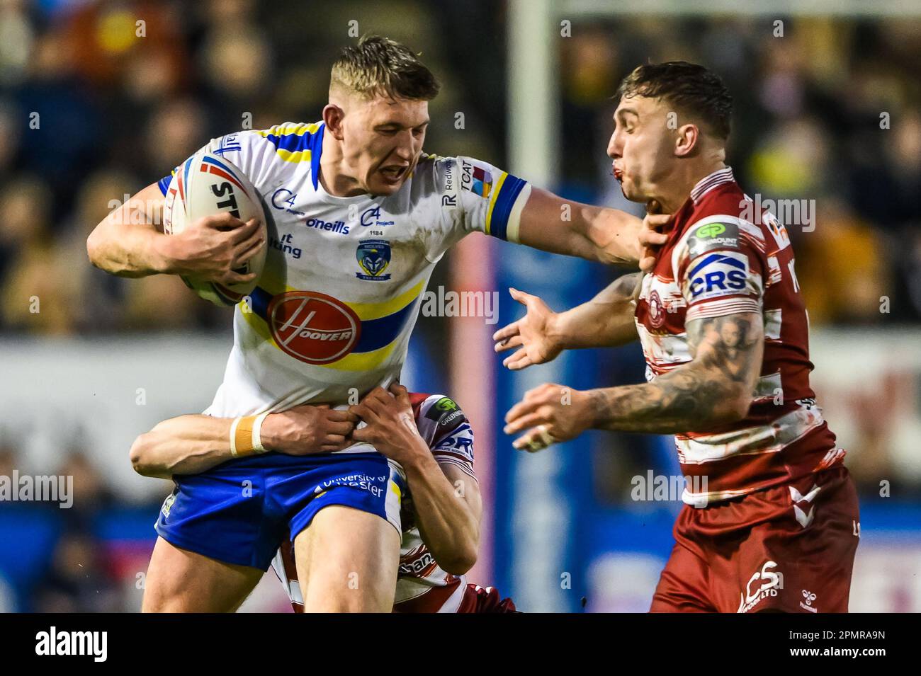 Matty Nicholson #12 of Warrington Wolves fends off Sam Powell #9 of ...