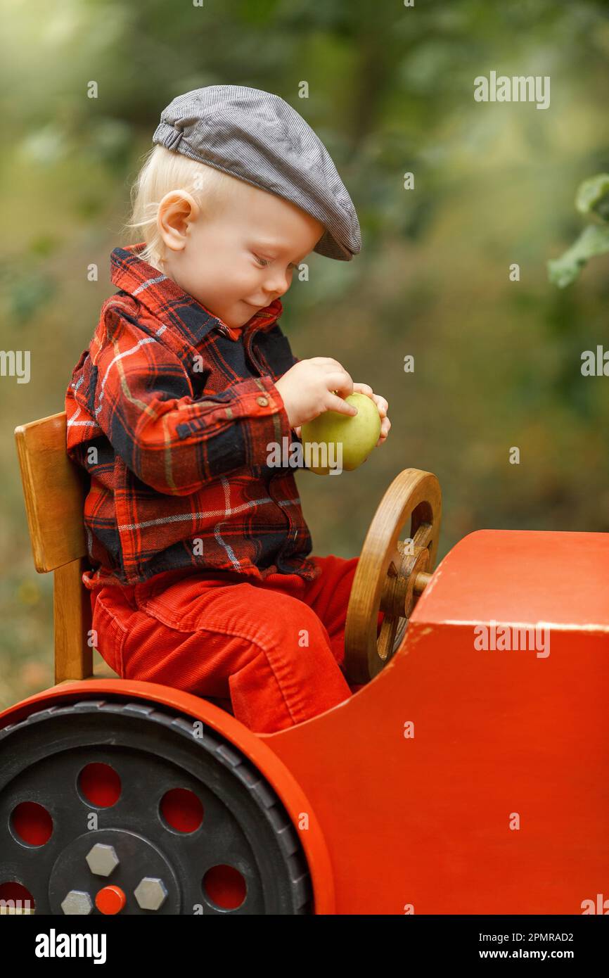 Farmer boy on a small red wooden tractor Stock Photo - Alamy