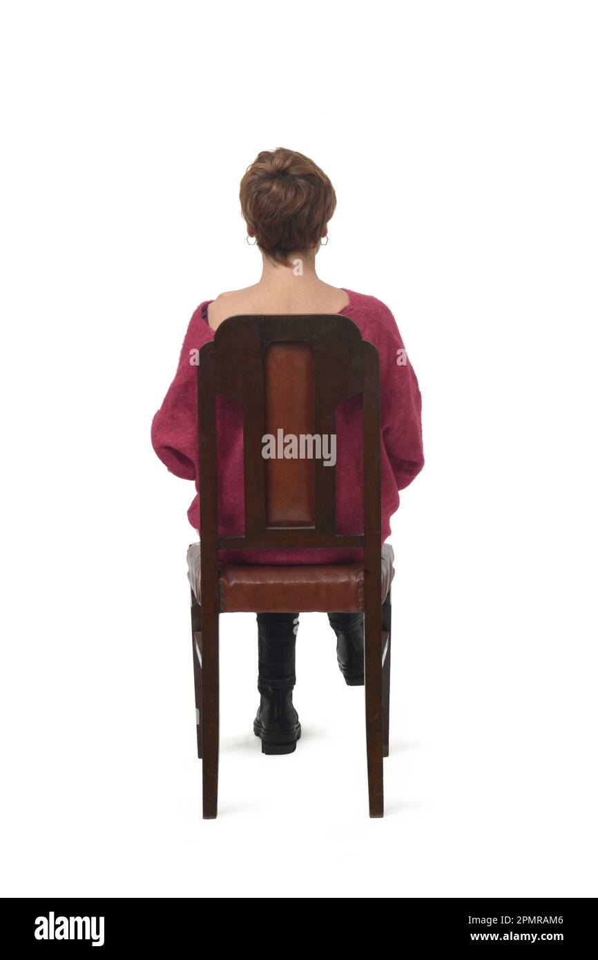 back view of a woman in tight jean pants sitting on chair cross legged ...