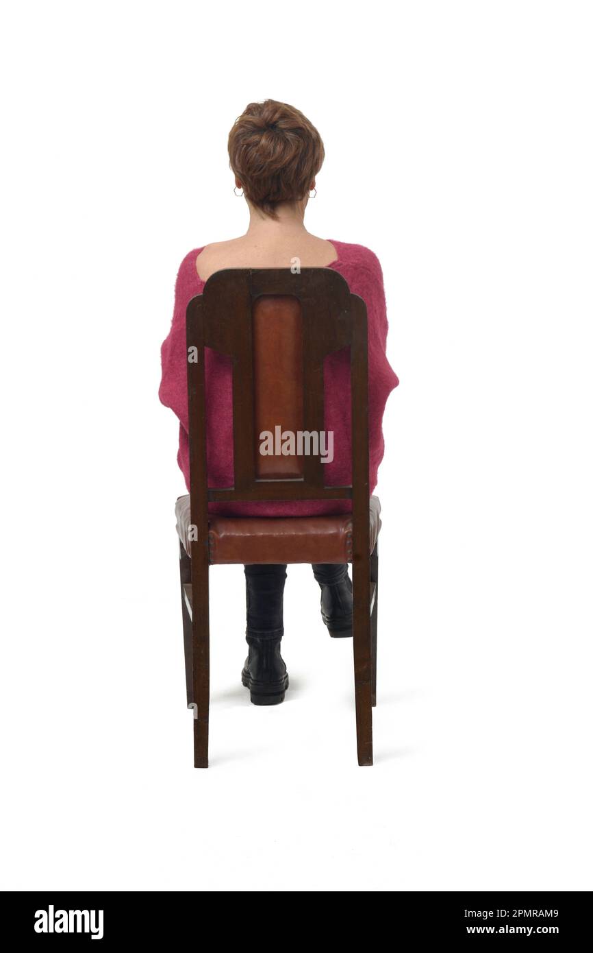 back view of a woman in tight jean pants sitting on chair cross legged ...