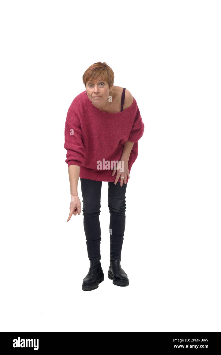 crouched woman looking at camera and pointing finger at ground on white ...