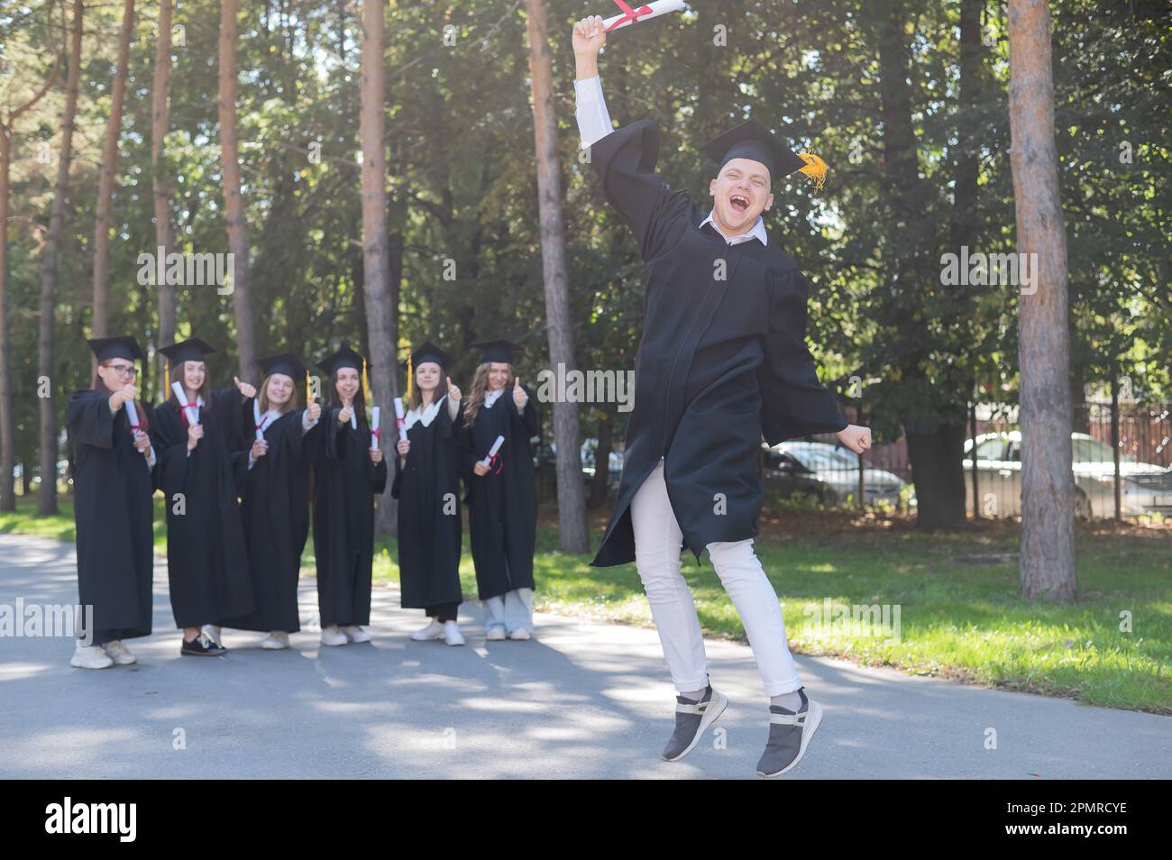 Happy young caucasian man celebrating graduation. Crowd of students ...