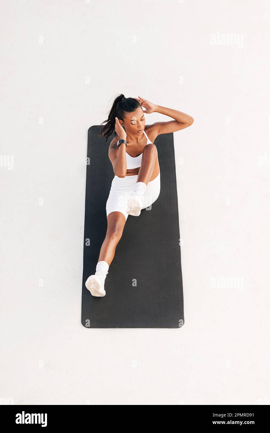Young female doing core exercises on a mat outdoors. High angle of a ...