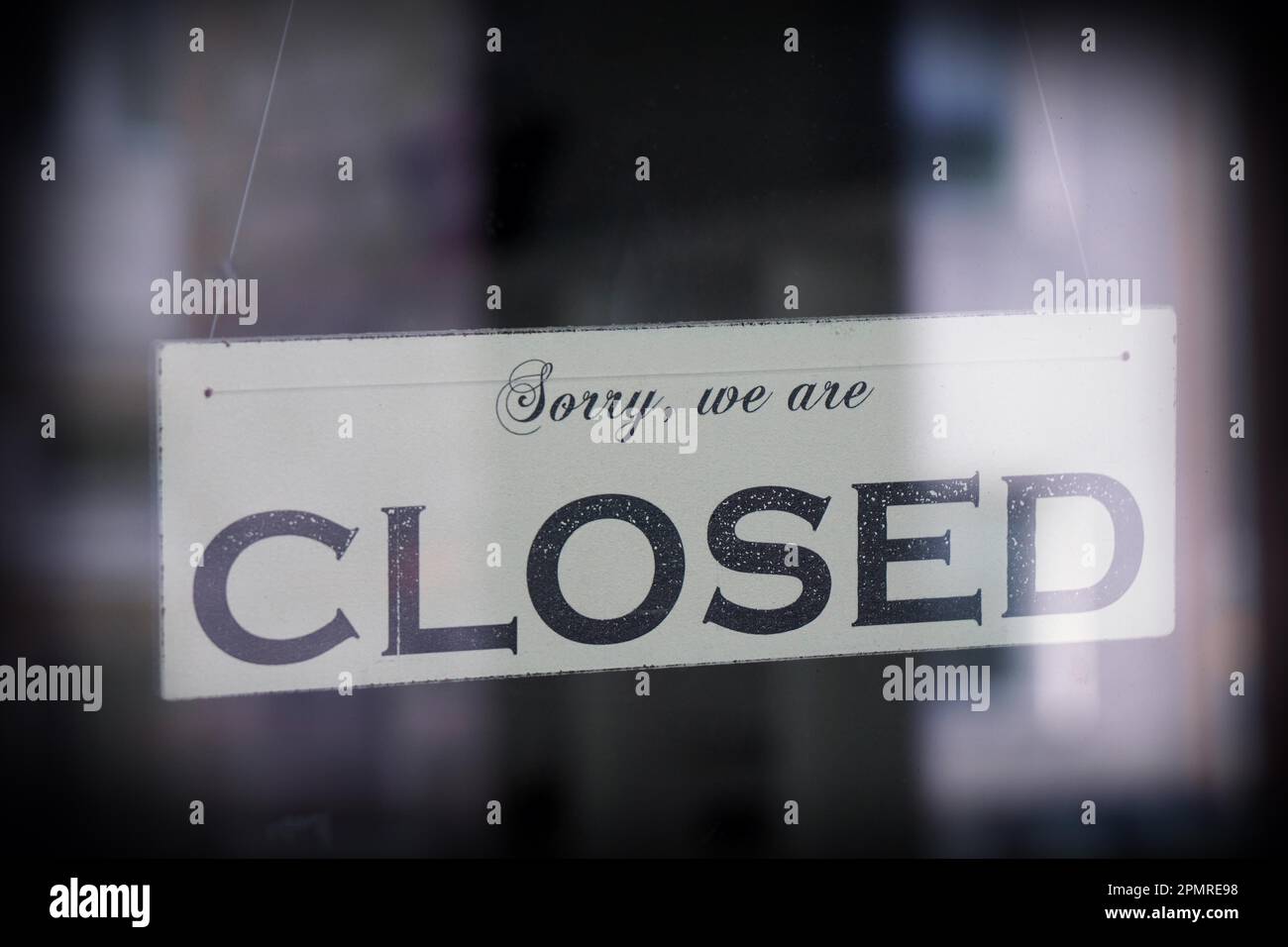 sign saying sorry we are closed, behind glass with reflection ...