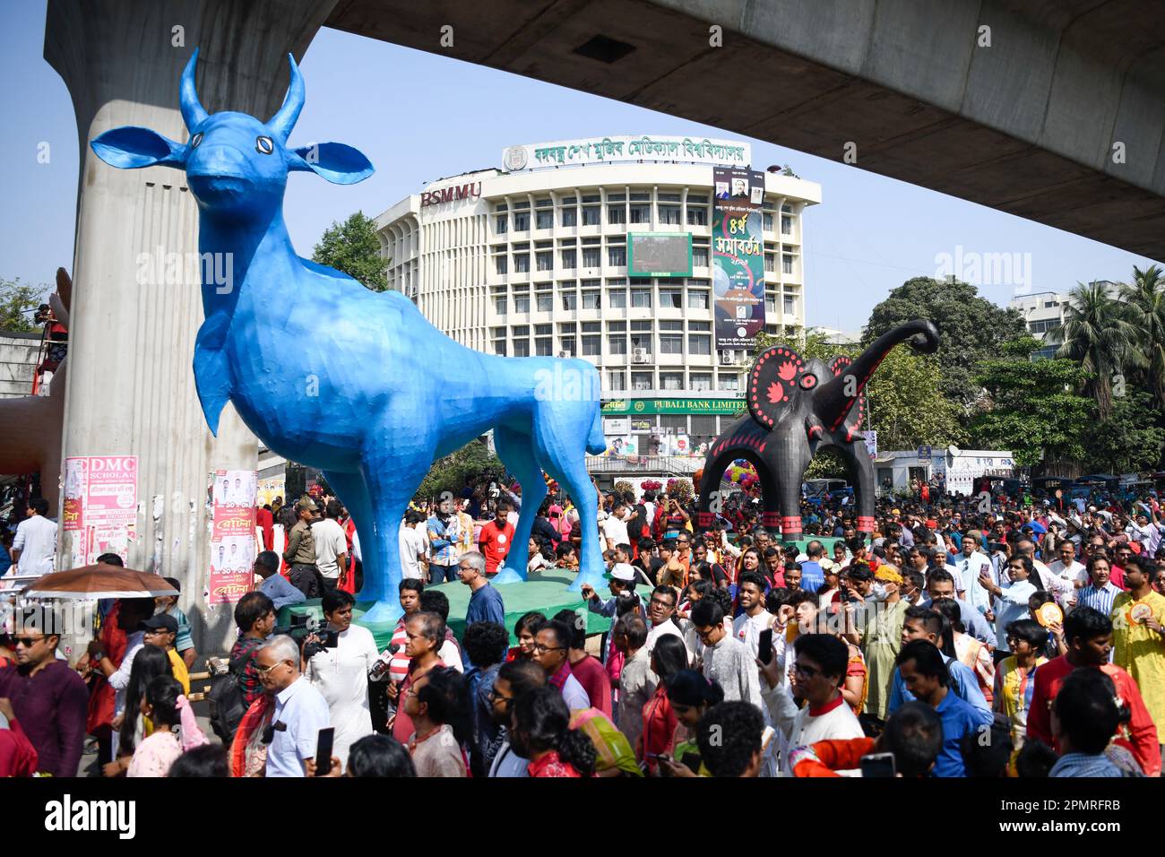Bangladeshi people participate in a colorful rally with a cartoon of a ...