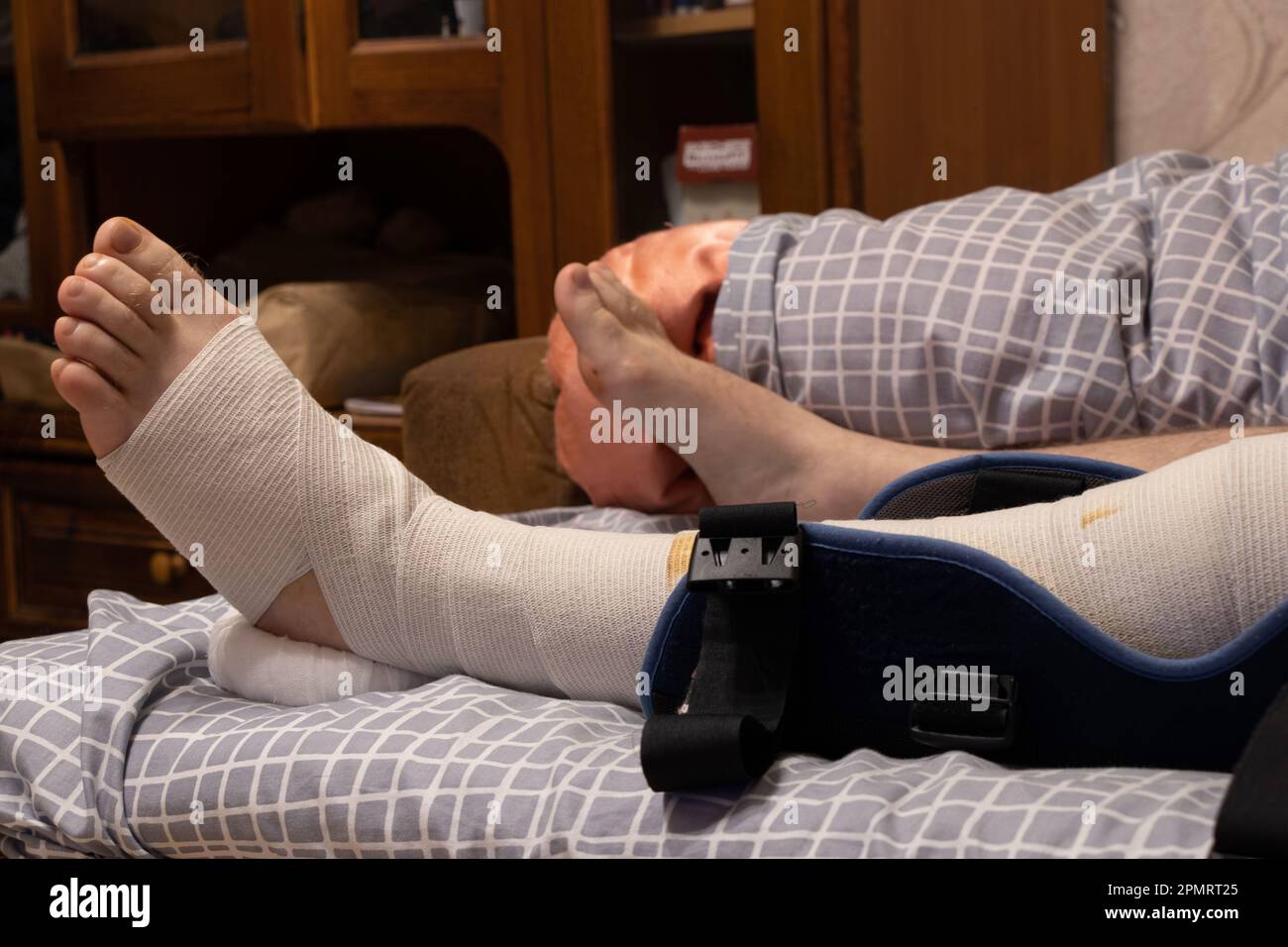 Man's leg with an elastic bandage and a knee orthosis after replacing ...