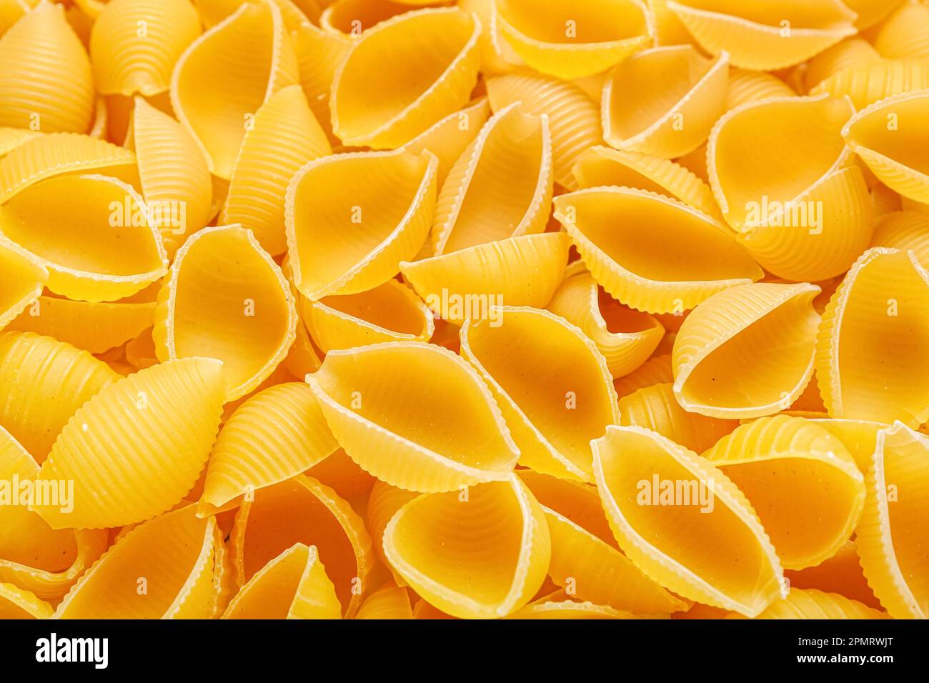 Raw conchiglie pasta as background Stock Photo - Alamy