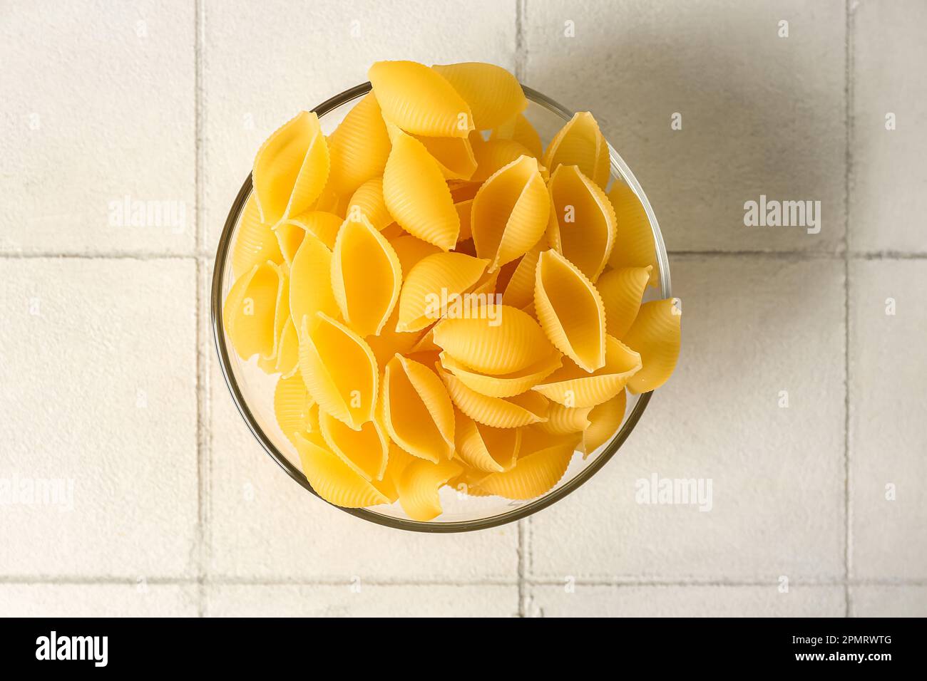 Bowl with raw conchiglie pasta on white tile background Stock Photo - Alamy