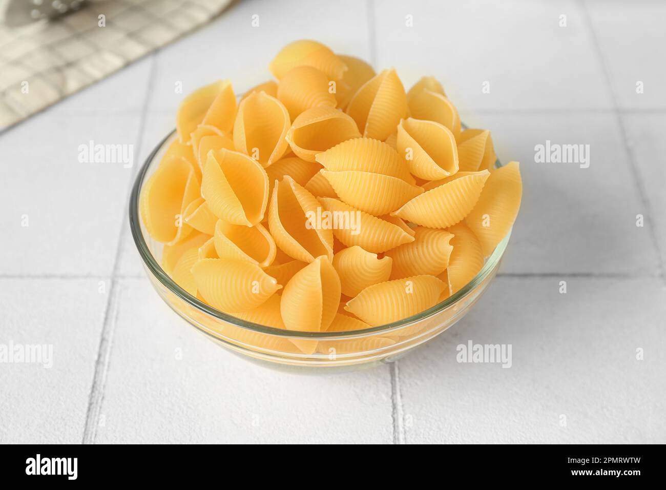 Bowl with raw conchiglie pasta on white tile background Stock Photo - Alamy