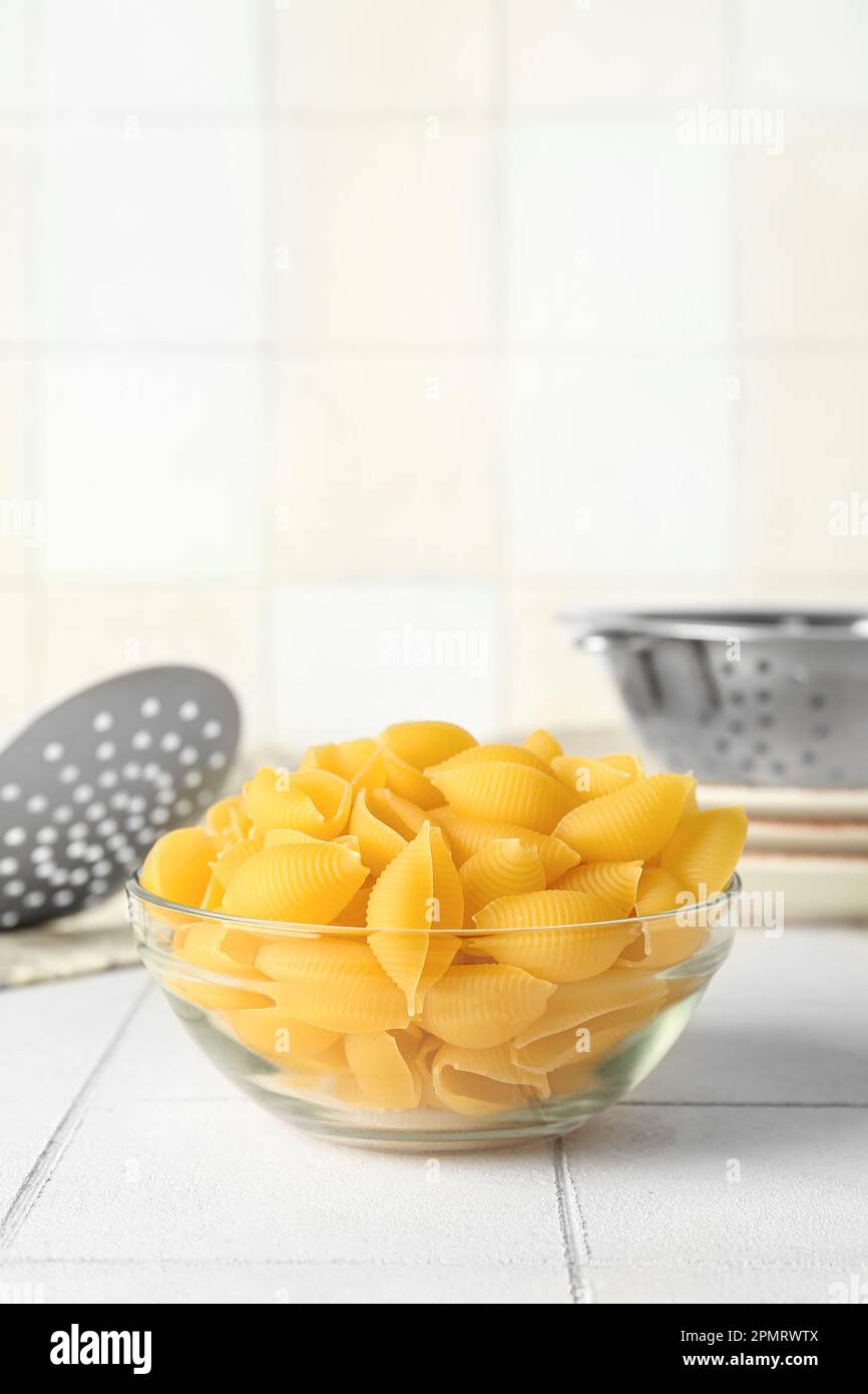 Bowl with raw conchiglie pasta on white tile background Stock Photo - Alamy