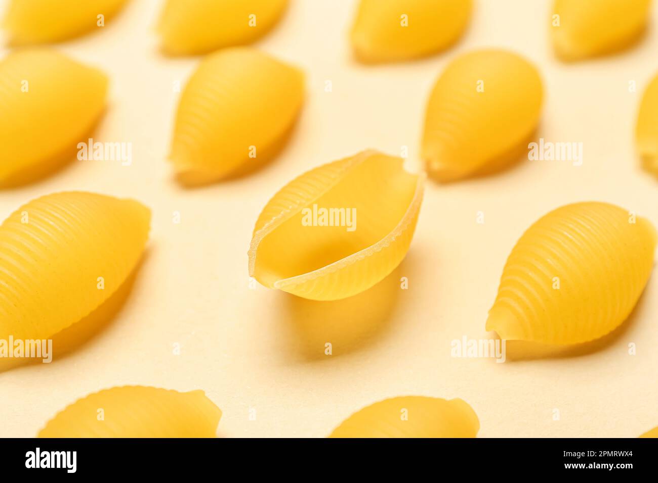 Raw conchiglie pasta on yellow background Stock Photo - Alamy