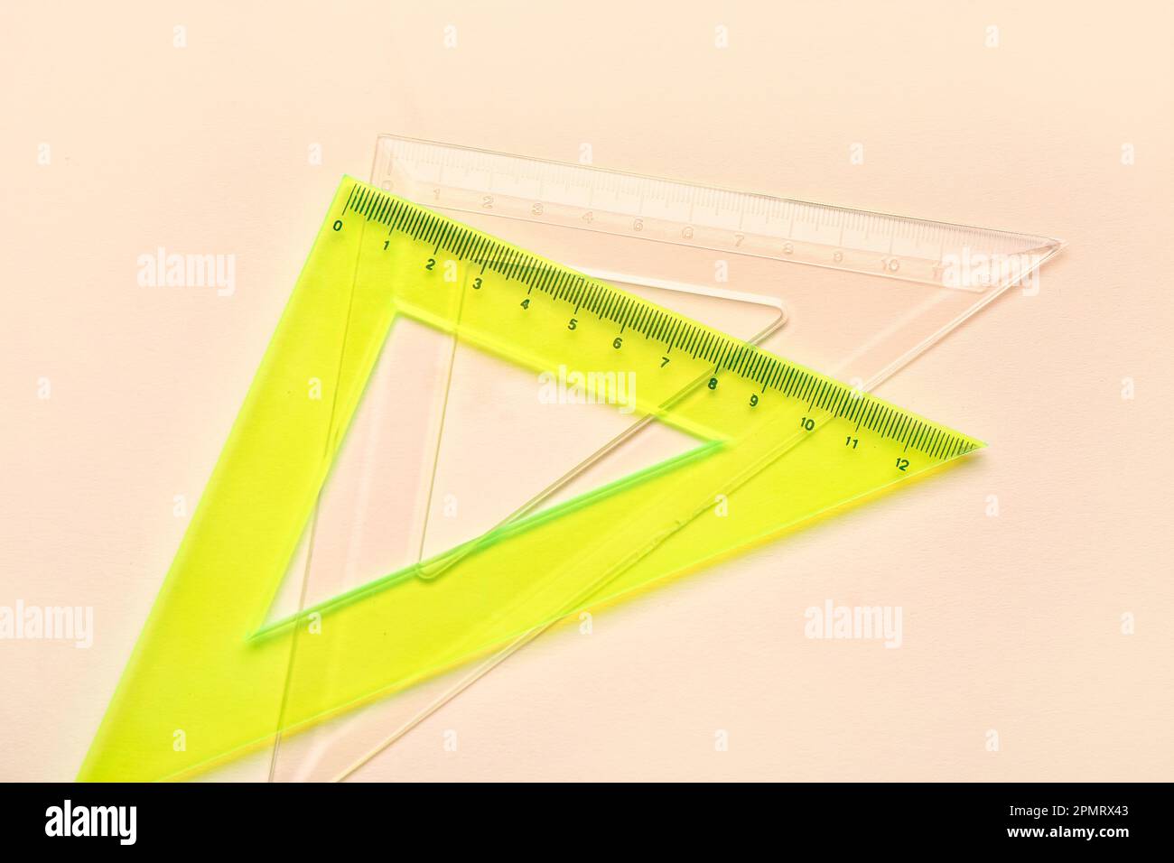 Transparent and yellow triangle plastic rulers on beige background ...