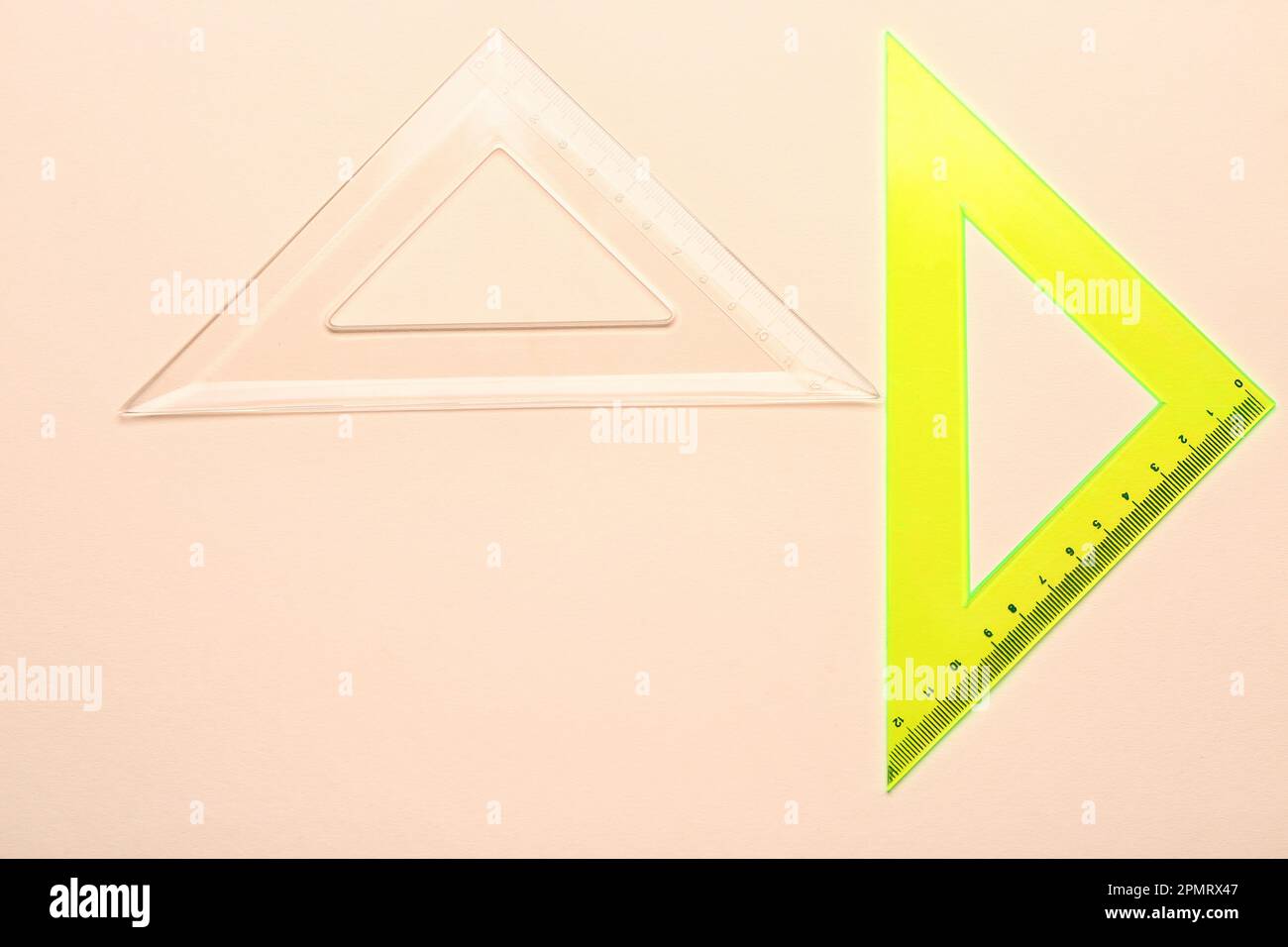 Transparent and yellow triangle plastic rulers on beige background ...