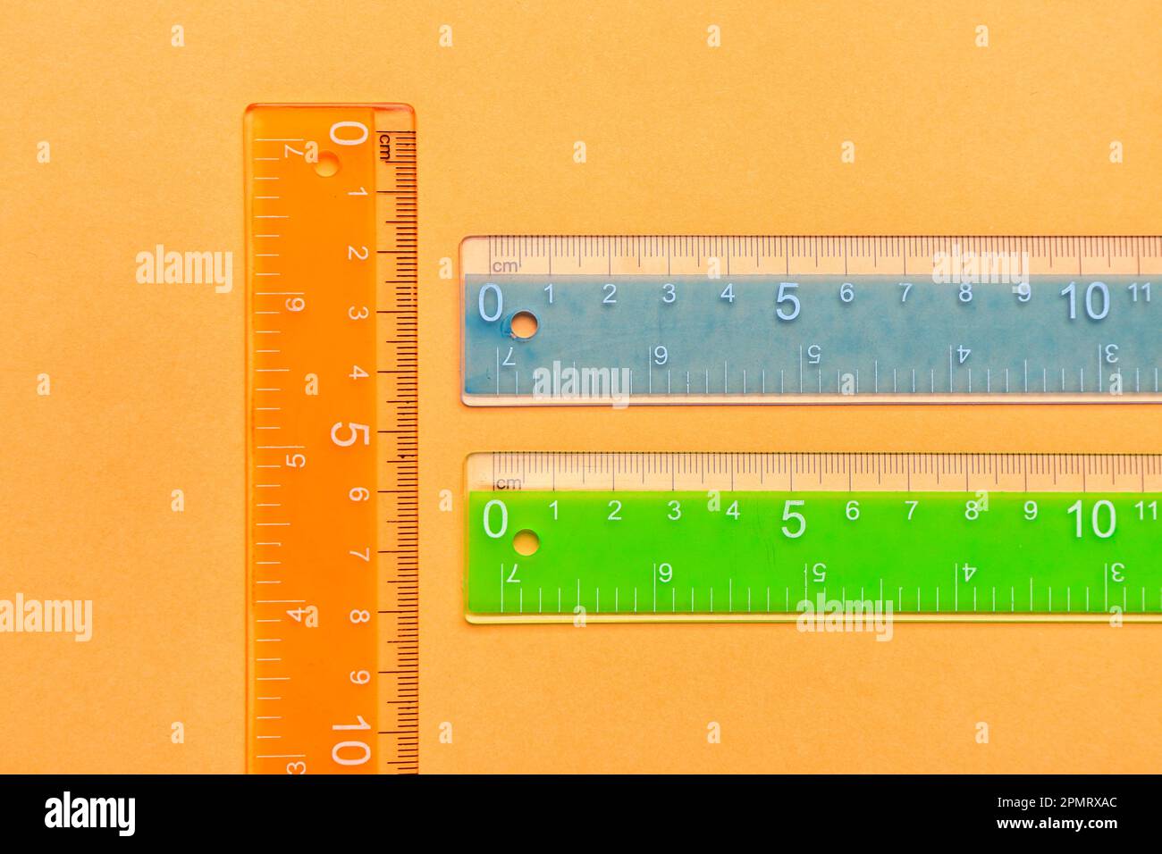 Colorful plastic rulers on orange background Stock Photo - Alamy
