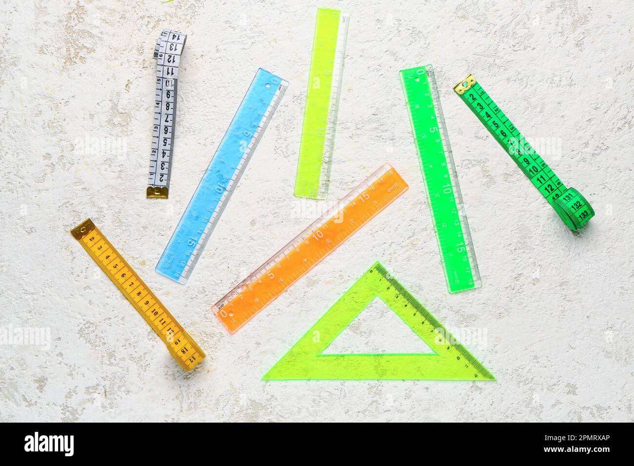 Colorful plastic rulers and measuring tapes on light grunge background ...