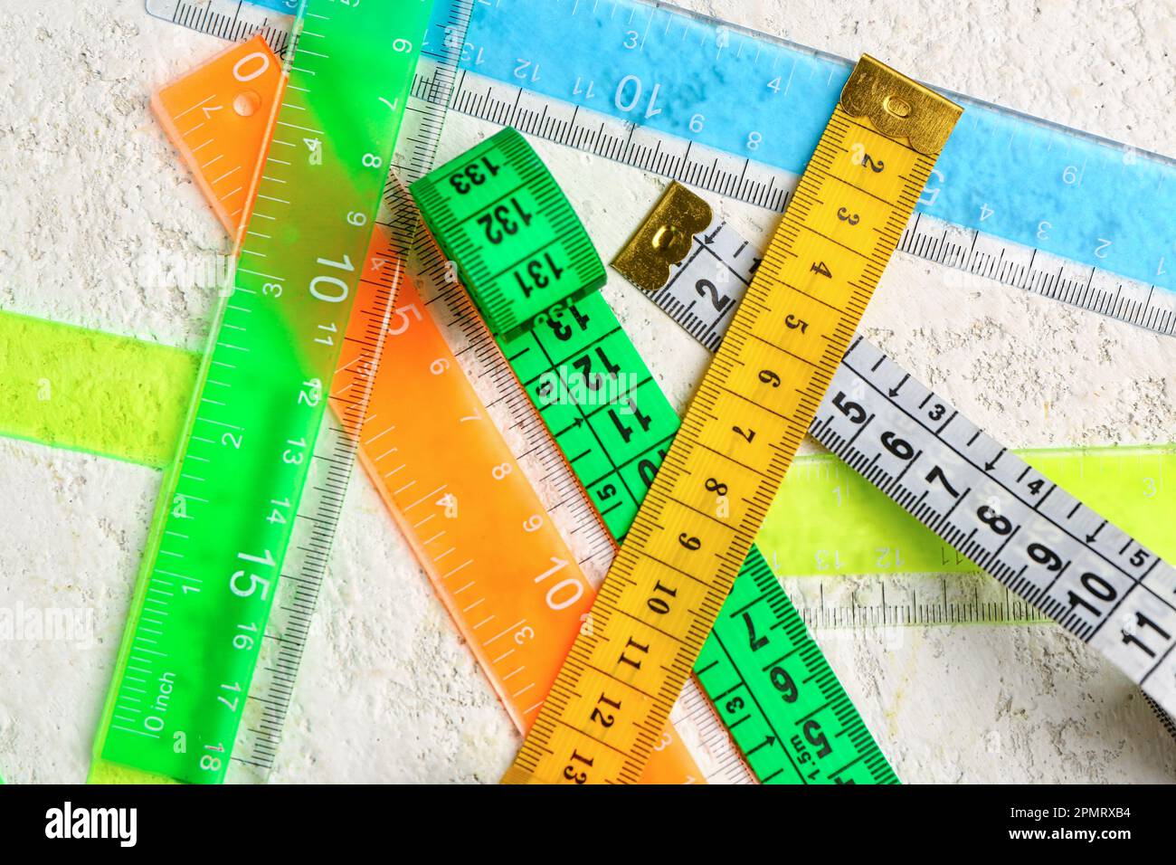 Colorful plastic rulers and measuring tapes on light grunge background ...