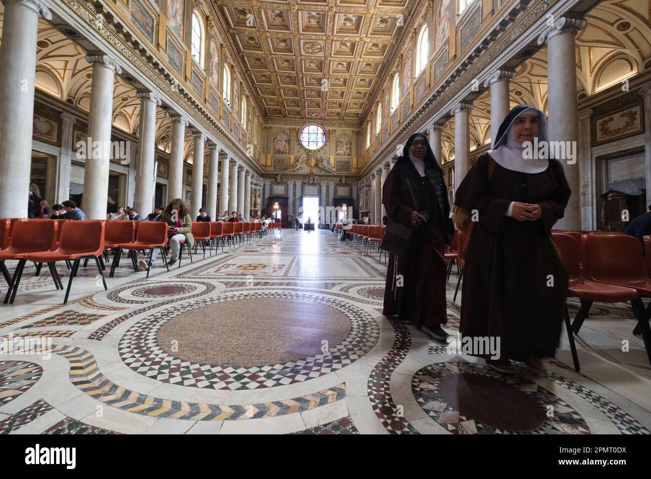 Two nuns walk in through the interior of the Basilica of Santa Maria ...