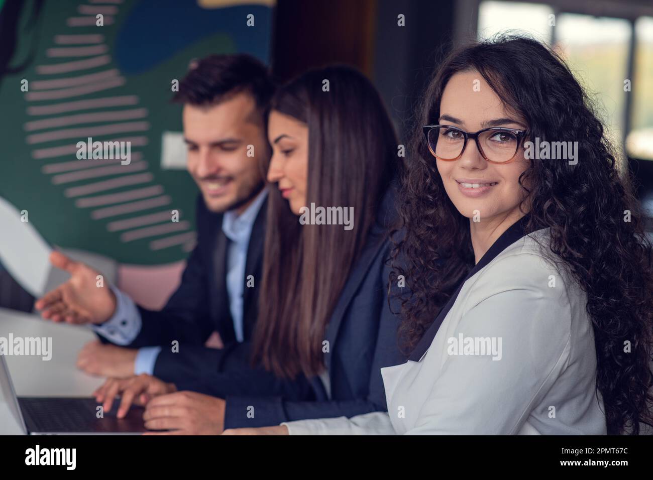 Business team collaborating on project together, using laptops ...