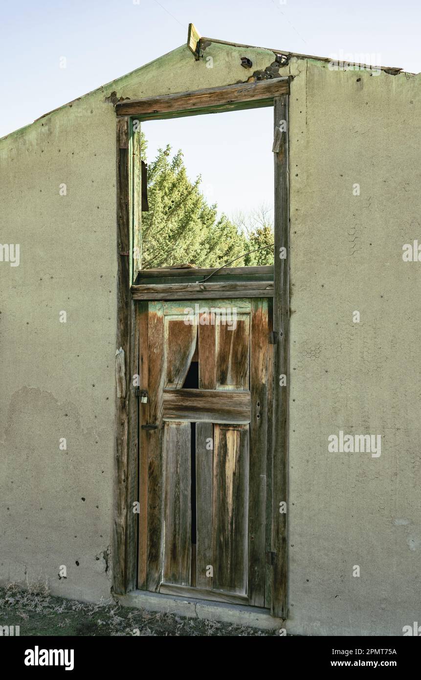 The wood door of an abandoned building is locked & above is an open ...