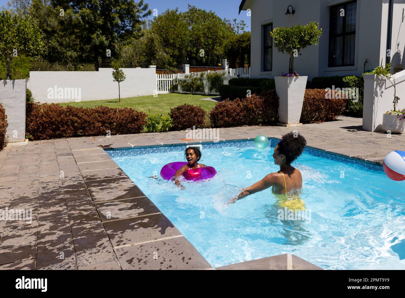 Happy Biracial Mother And Daughter Playing With Inflatables In Swimming