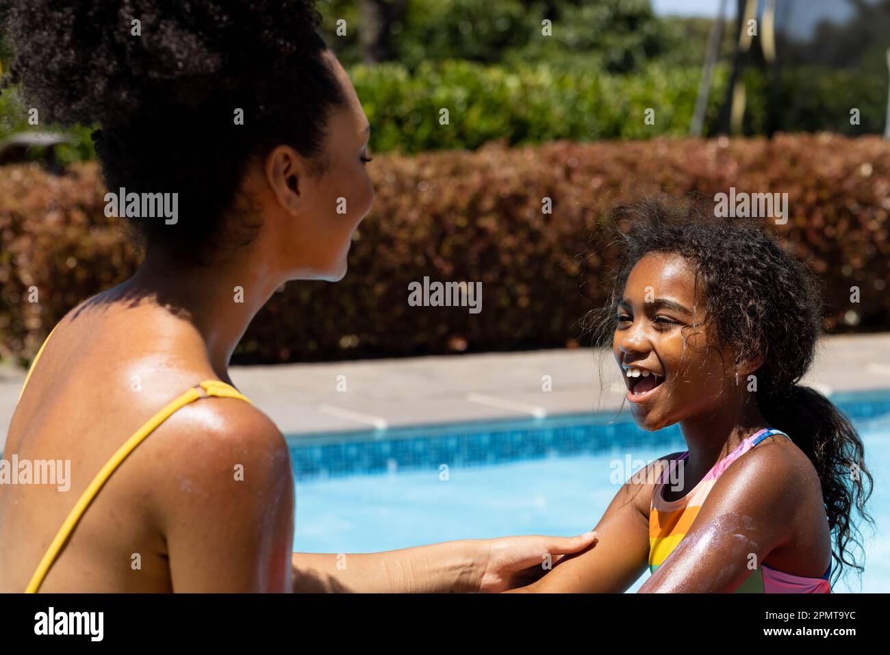 Happy Biracial Mother And Daughter Holding Hands By Swimming Pool In