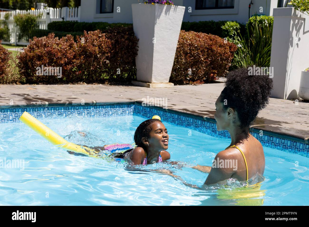 Happy Biracial Mother And Daughter Learning To Swim With Float In