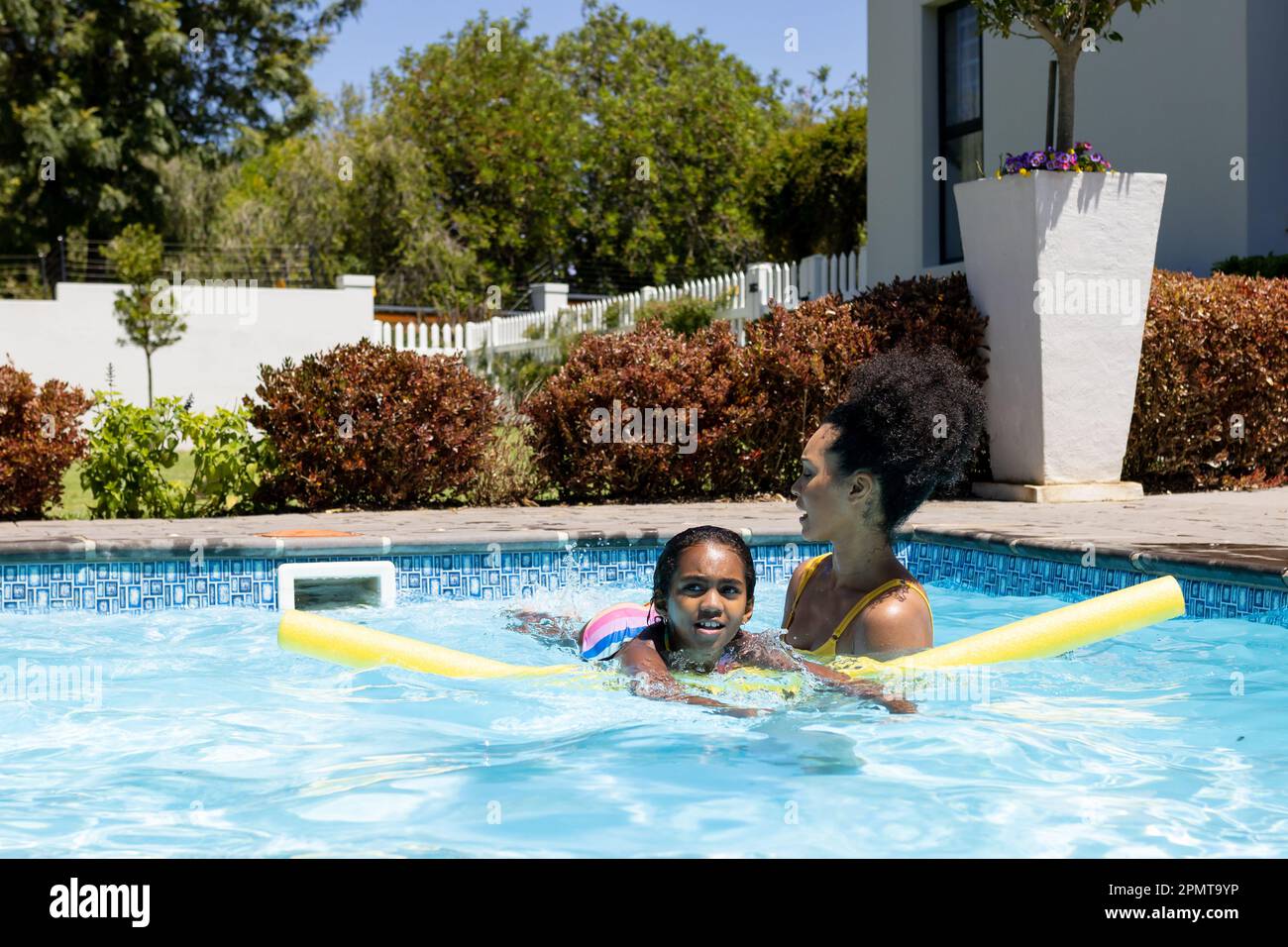 Happy Biracial Mother And Daughter Learning To Swim With Float In