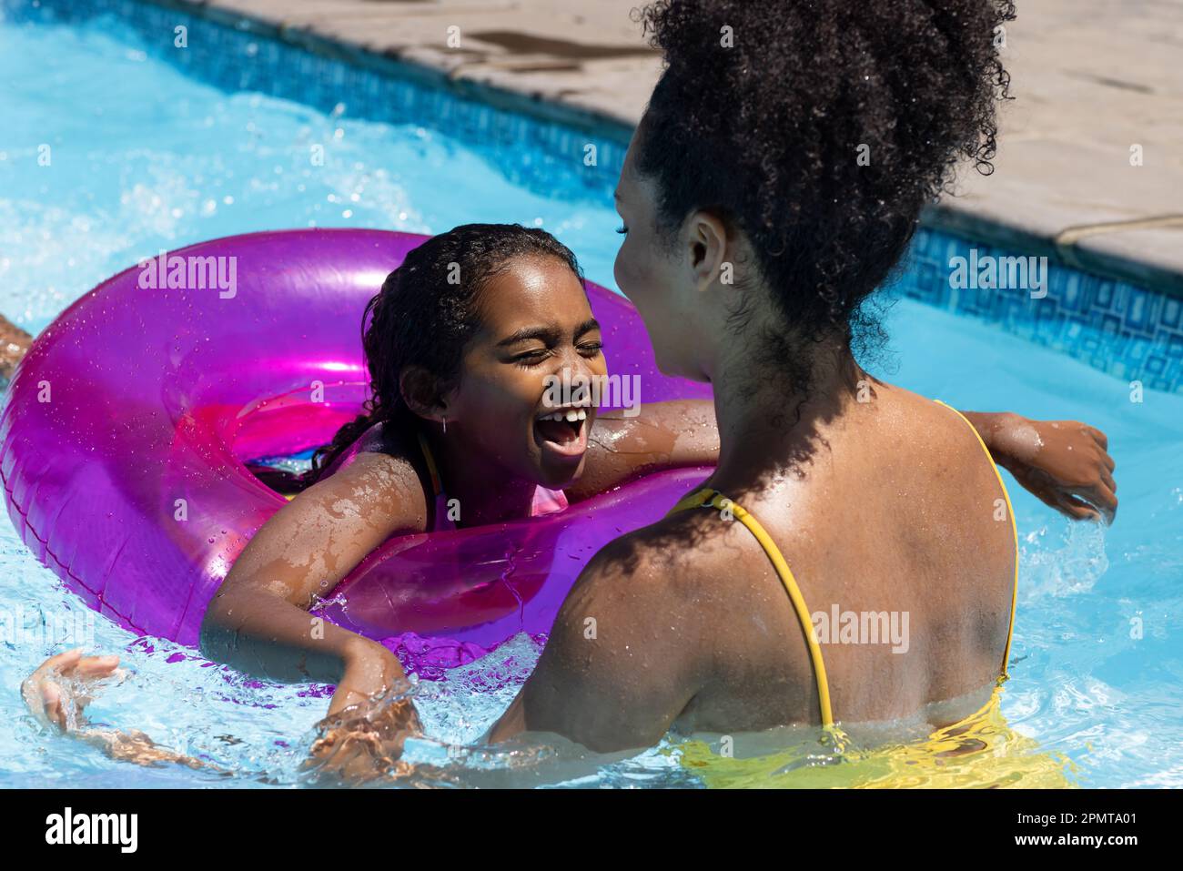 Happy Biracial Mother And Daughter Playing With Inflatable In Sunny