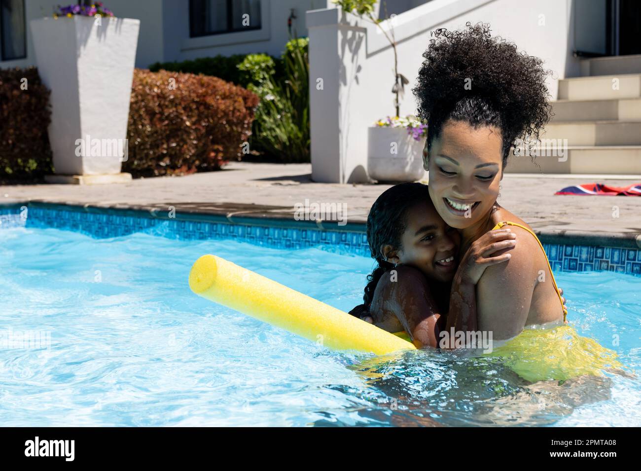Happy biracial mother and daughter learning to swim, hugging in ...