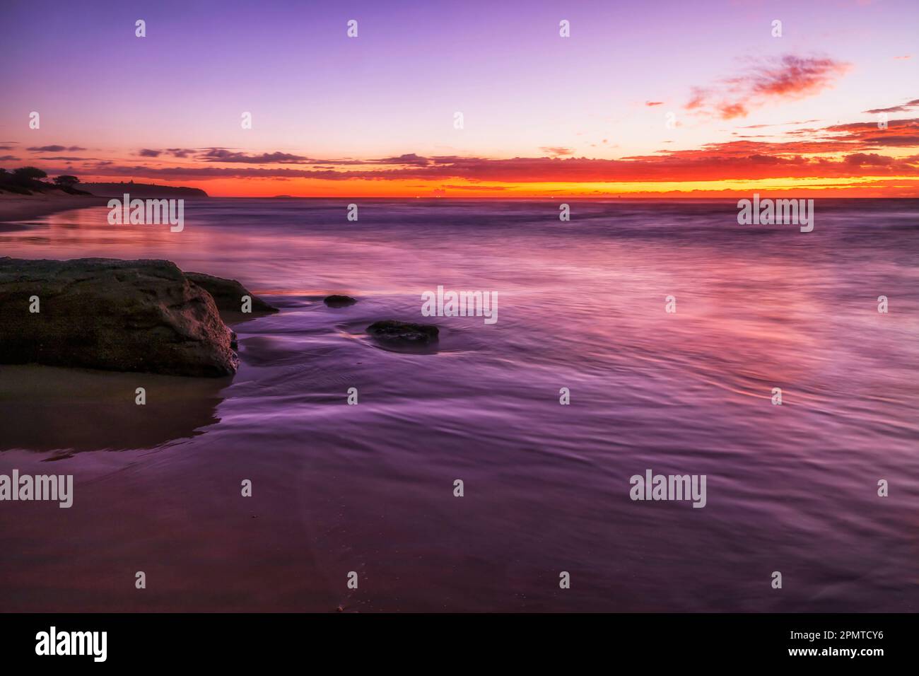 Scenic scarlett sunrise over Pacific ocean horizon at Caves beach of ...