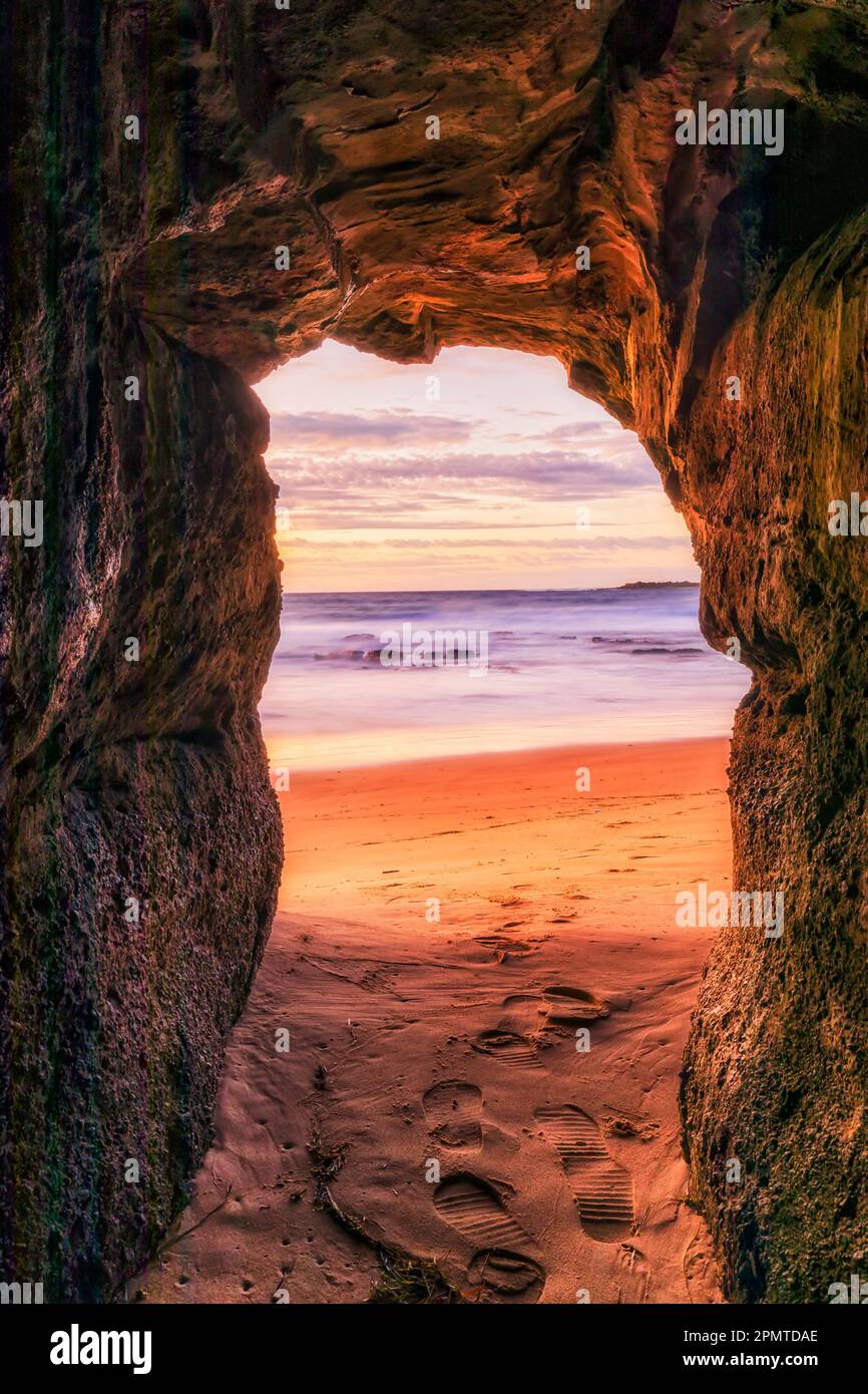 Natural arch window from Caves beach cave to sandy beach at sunrise on ...