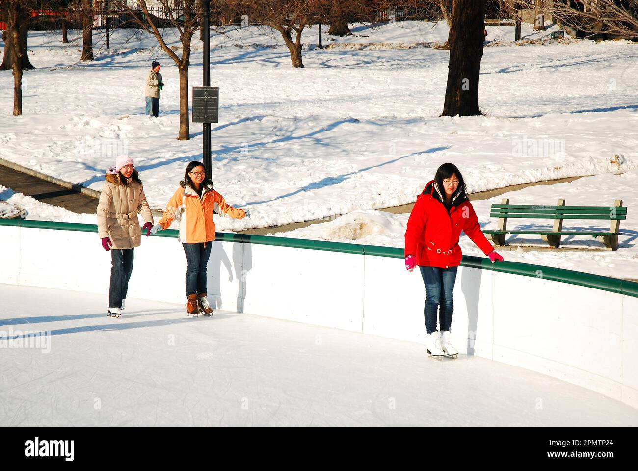 A group of novice ice skaters hold on to the side walls of the rink to ...