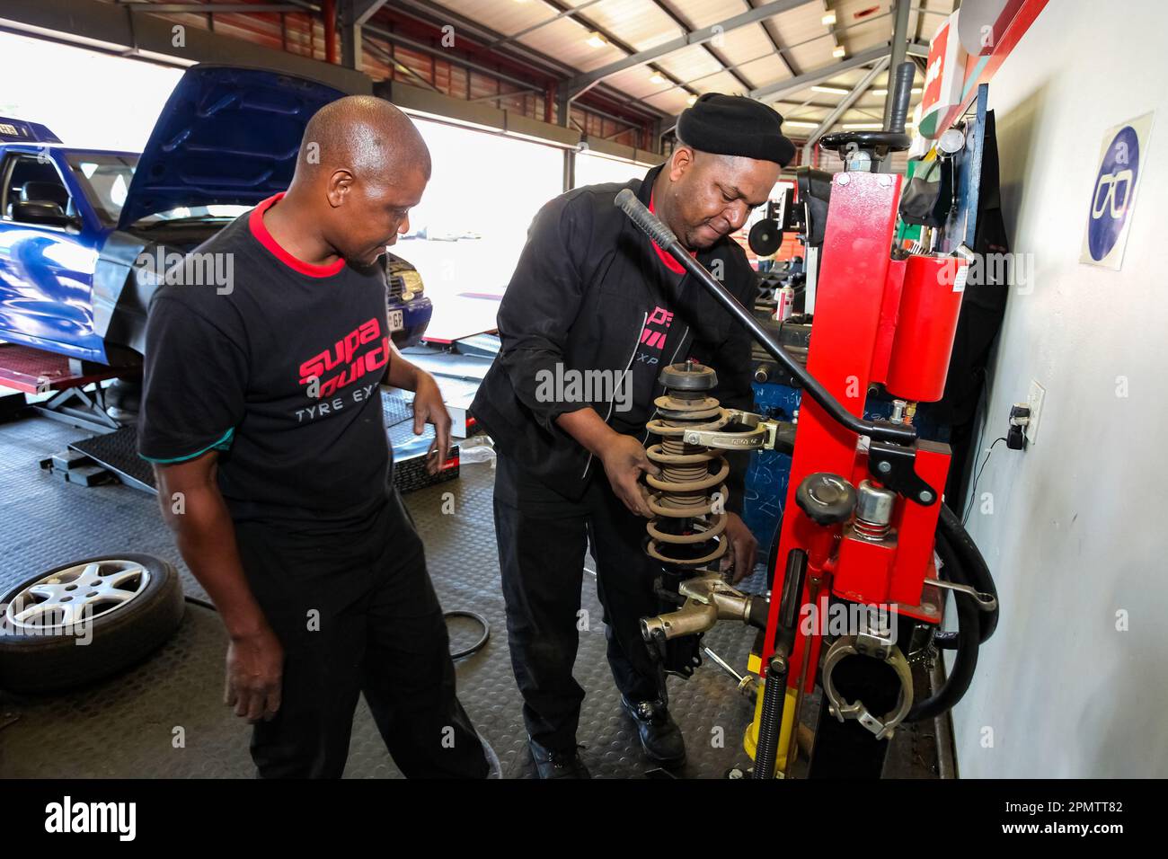 Two male mechanics wearing identical shirts perform maintenance on a ...