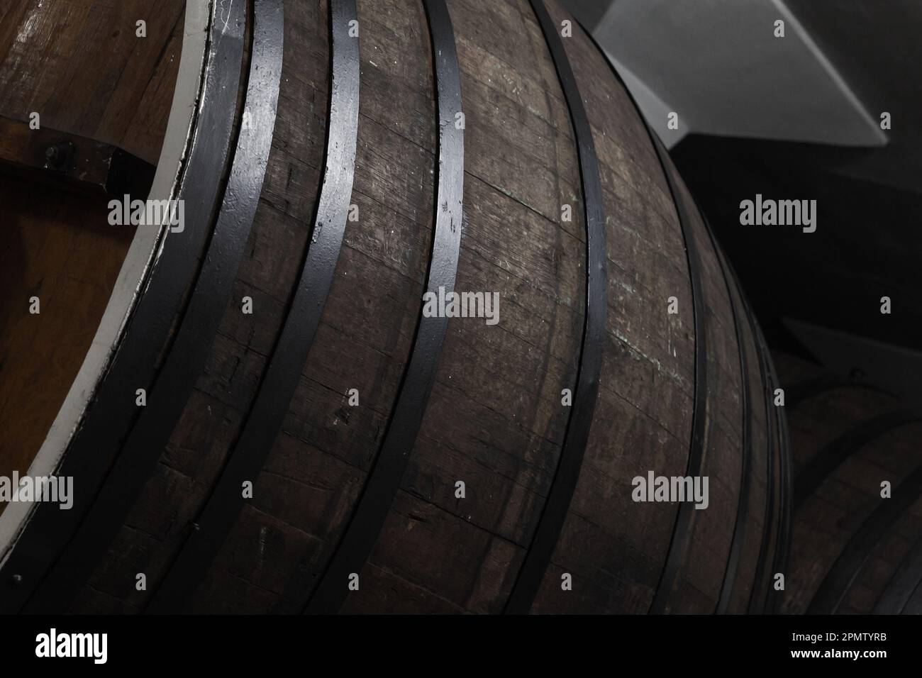 Old brown wooden barrel in dark winery, close-up photo with selective ...