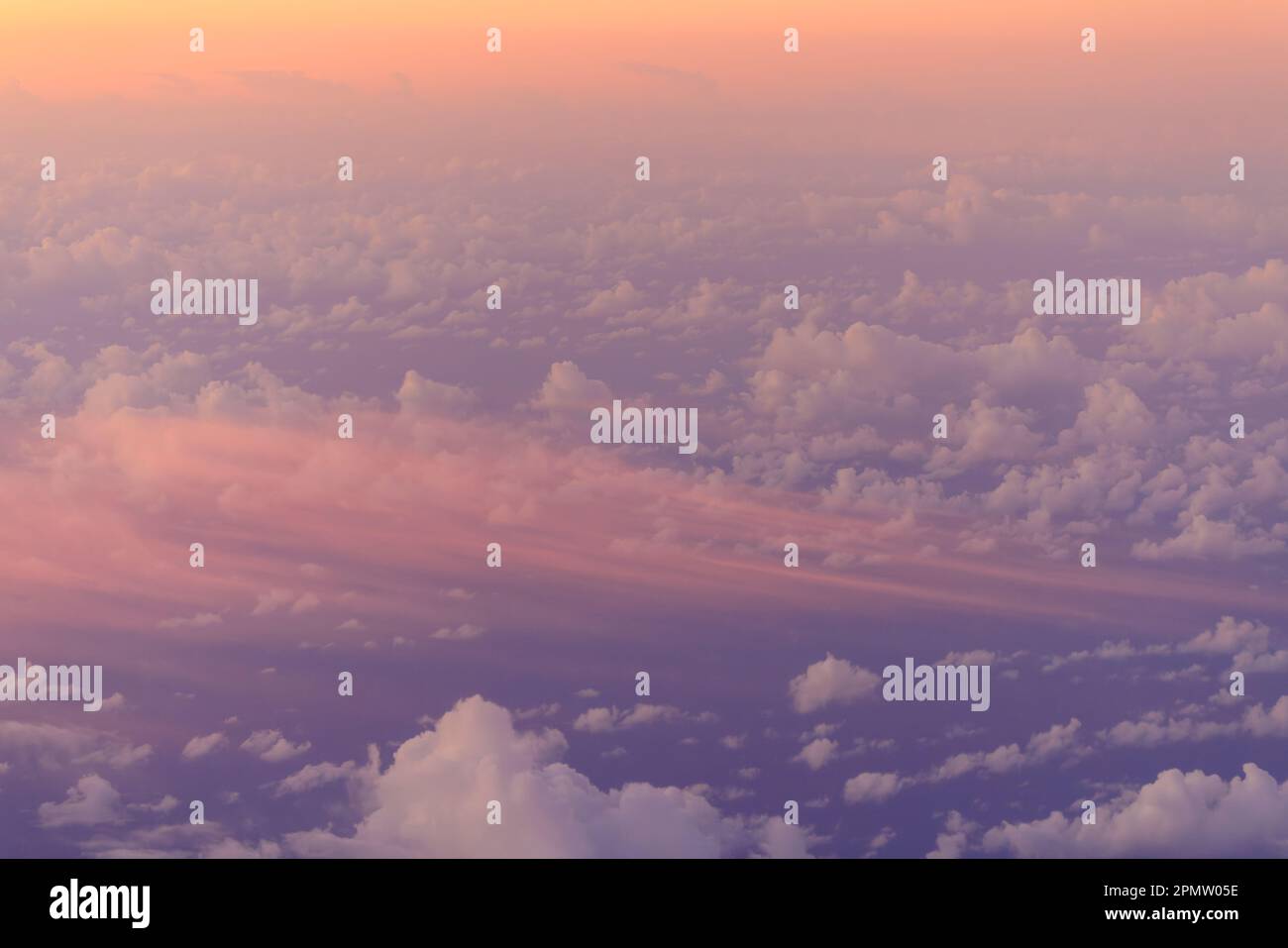 Wispy pink clouds glow at dawn over deep blue ocean at high elevation ...