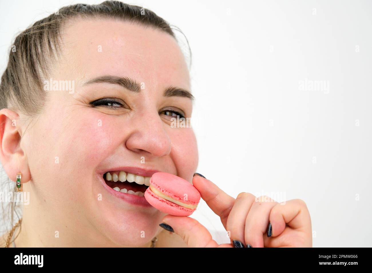 satisfied and happy woman eating macaroons on white background space ...